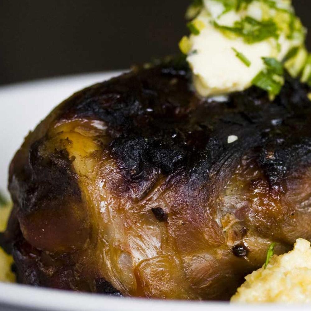 Roasted wild boar shank with green-flecked polenta